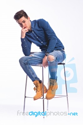 Male Model In Denim Jeans Sitting On A Chair . Studio Shoot Stock Photo ...